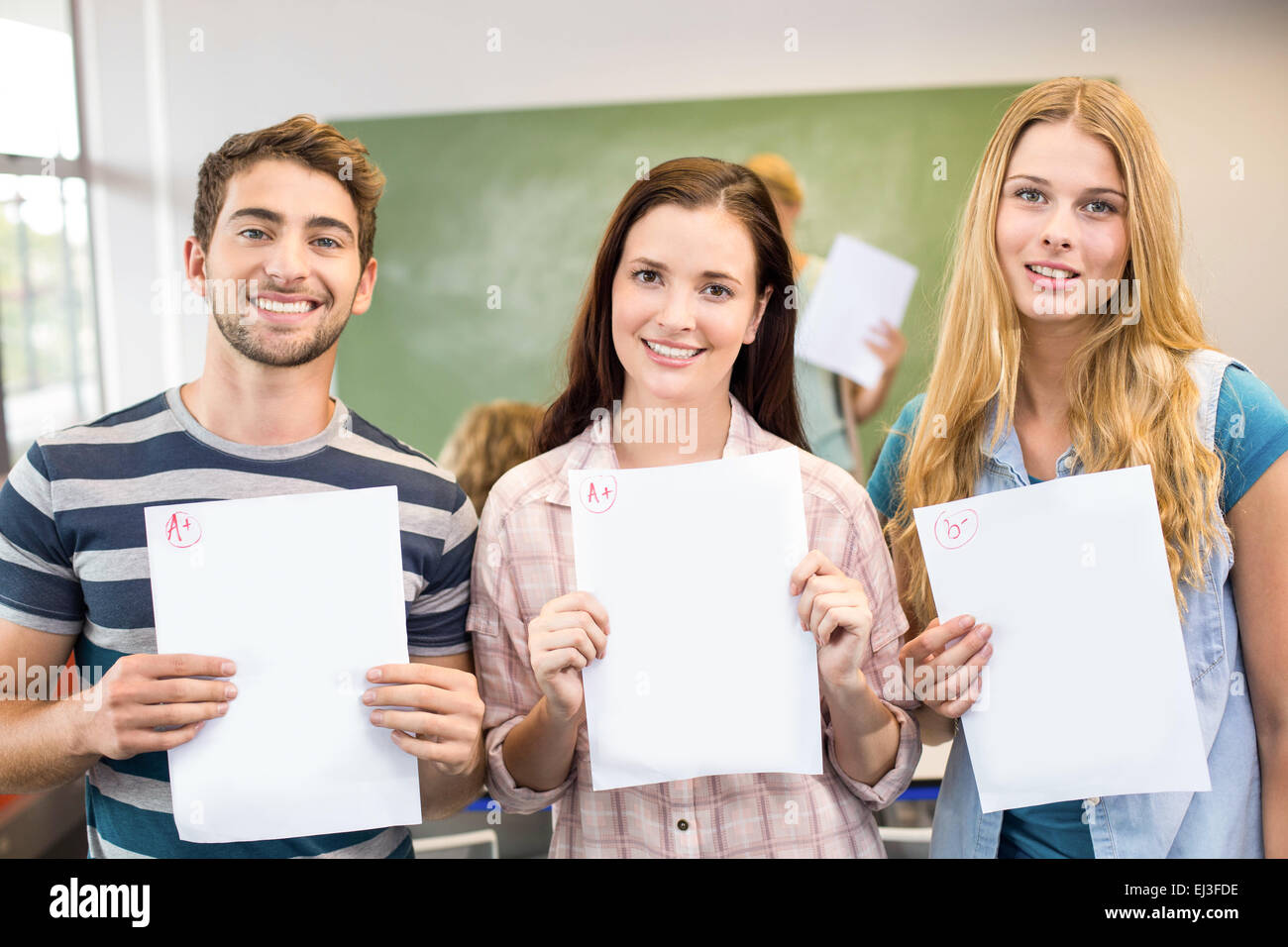 Happy students holding papers in class Stock Photo - Alamy