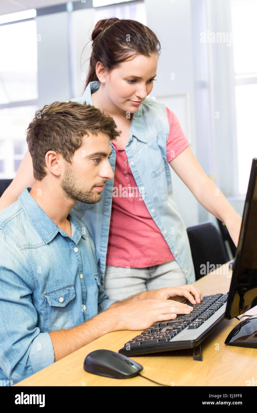Computer teacher helping pretty female student Stock Photo - Alamy