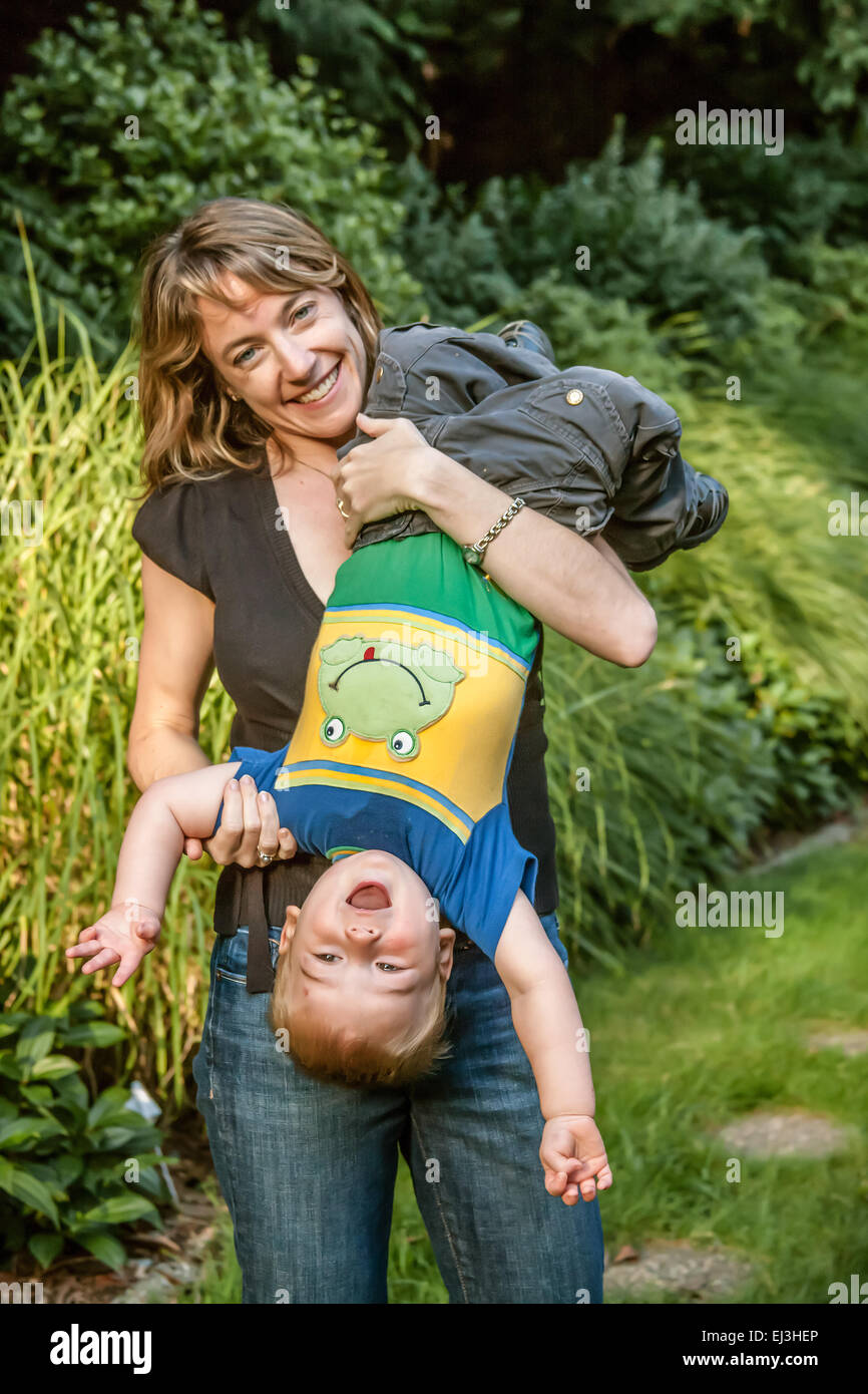 Mother roughhousing with her 18 month old son, turning him upside down ...