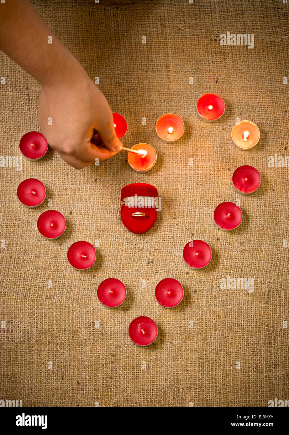 Closeup photo of person lighting decorative candles around ring in box ...