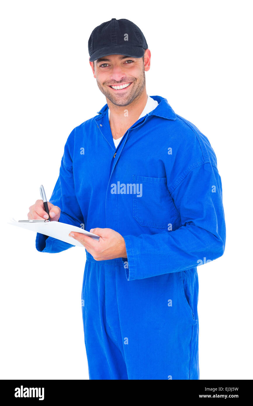 Handyman in blue overall writing on clipboard Stock Photo - Alamy