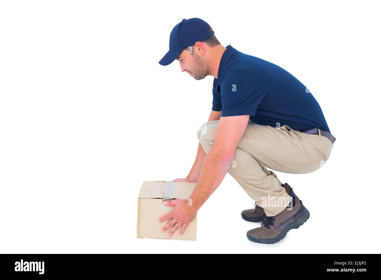 Delivery man crouching while picking cardboard box Stock Photo - Alamy
