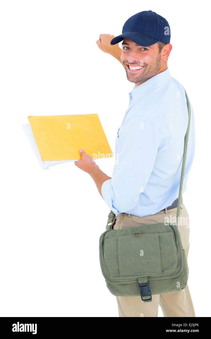 Smiling postman with letter knocking on white background Stock Photo ...