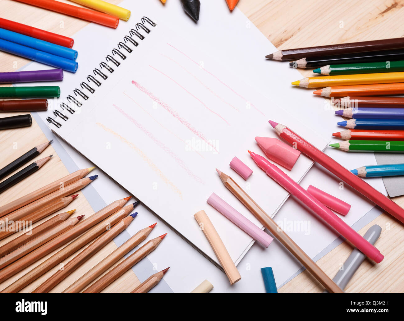 various drawing tools around white notebook and painted pink stripes ...