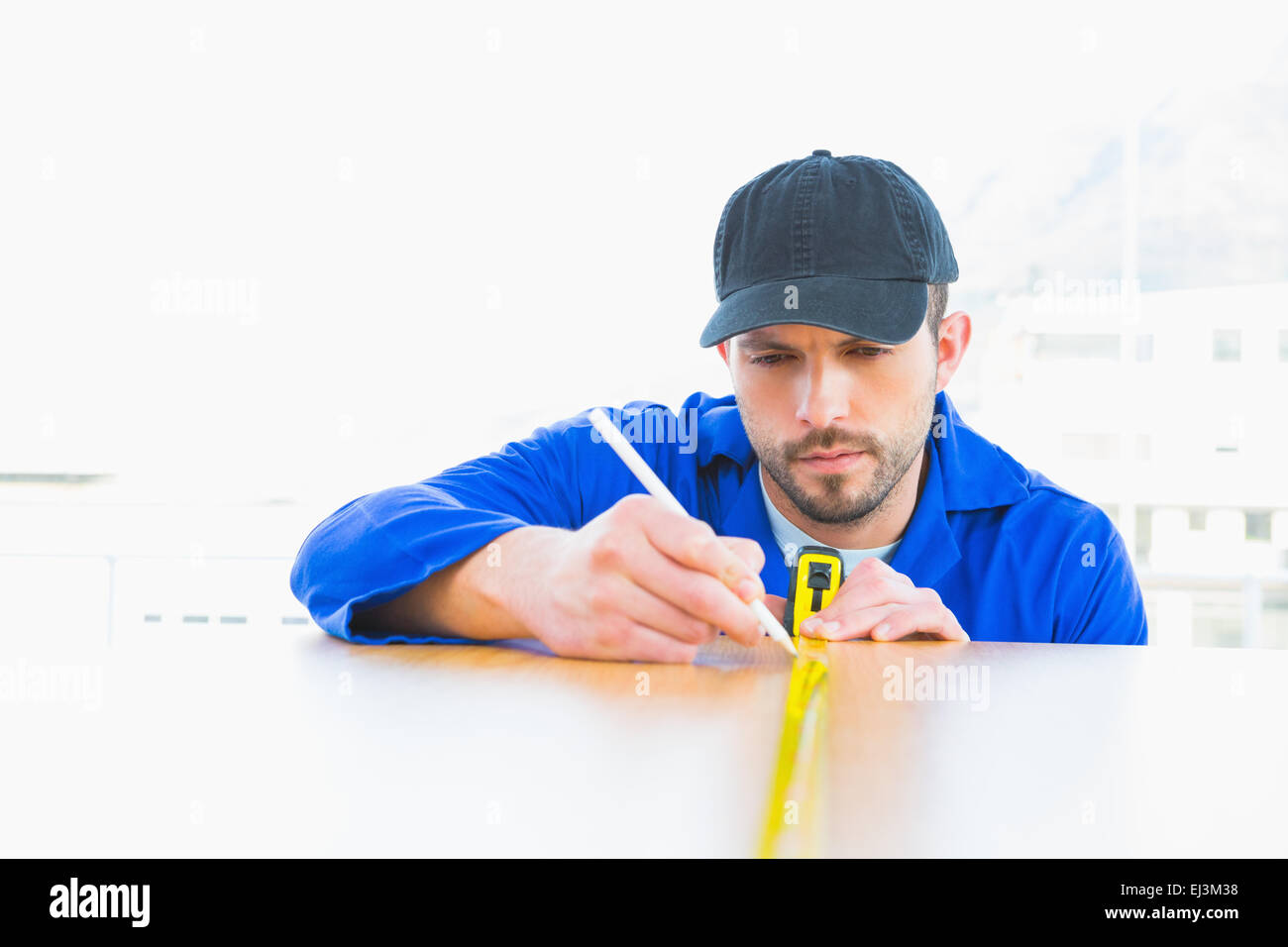 Handyman measuring wood board Stock Photo - Alamy