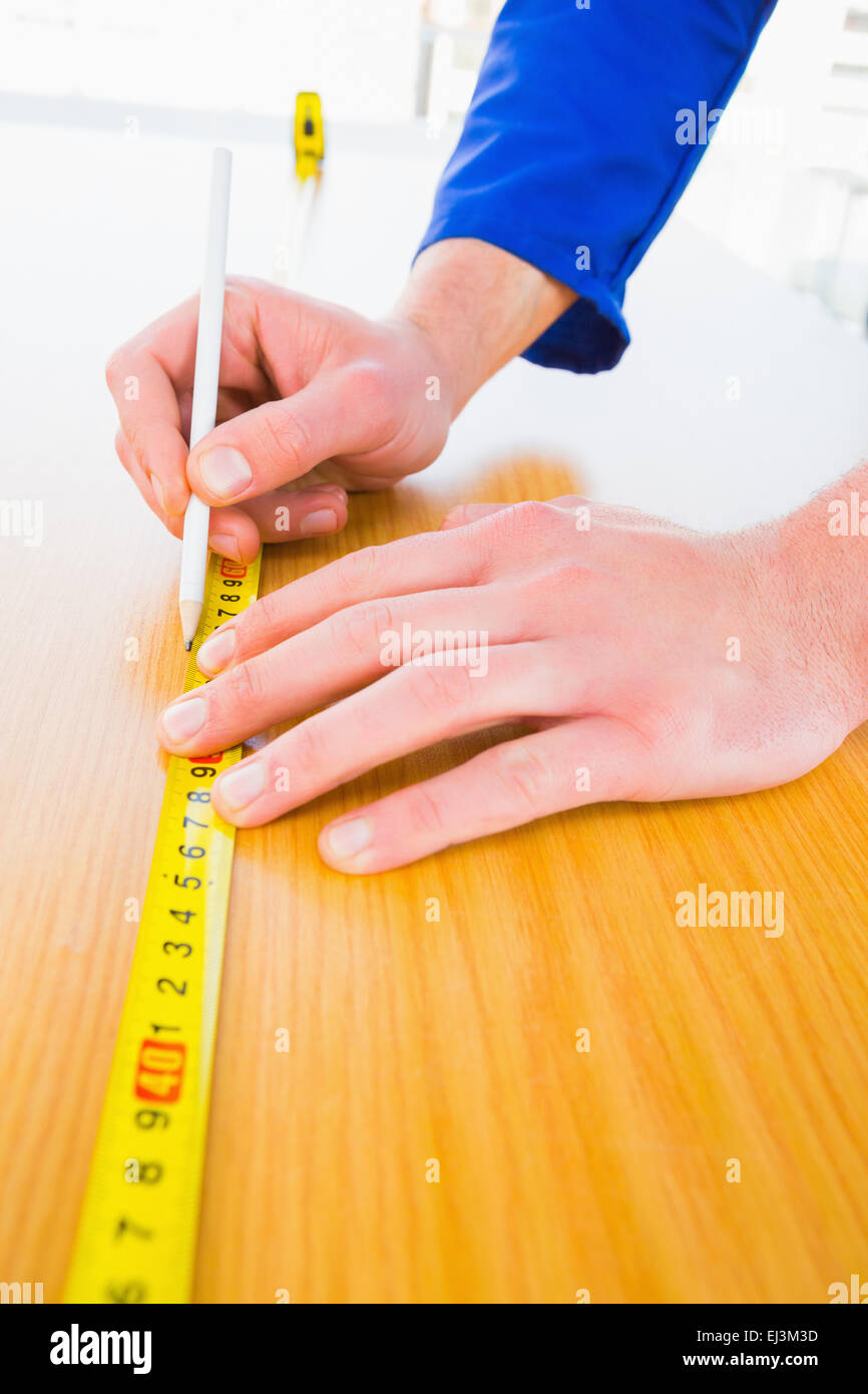 Handyman measuring wood board Stock Photo - Alamy