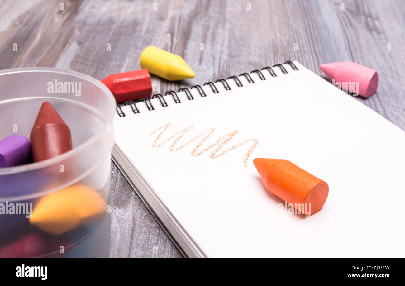 colorful crayons on the edge of white notebook on a wooden table Stock ...