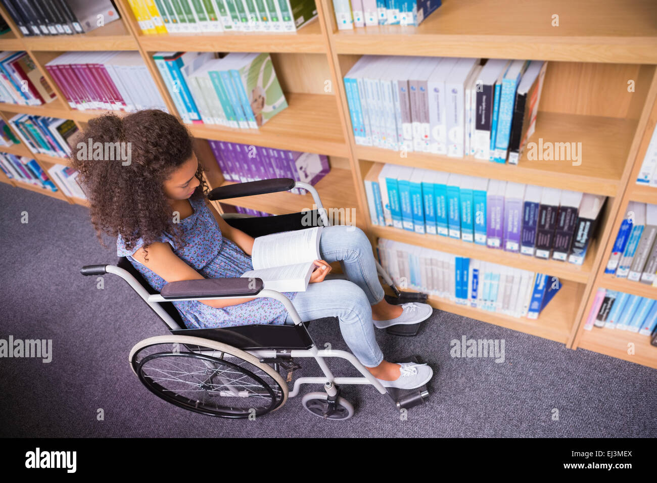 Smiling disabled student in library reading book Stock Photo - Alamy