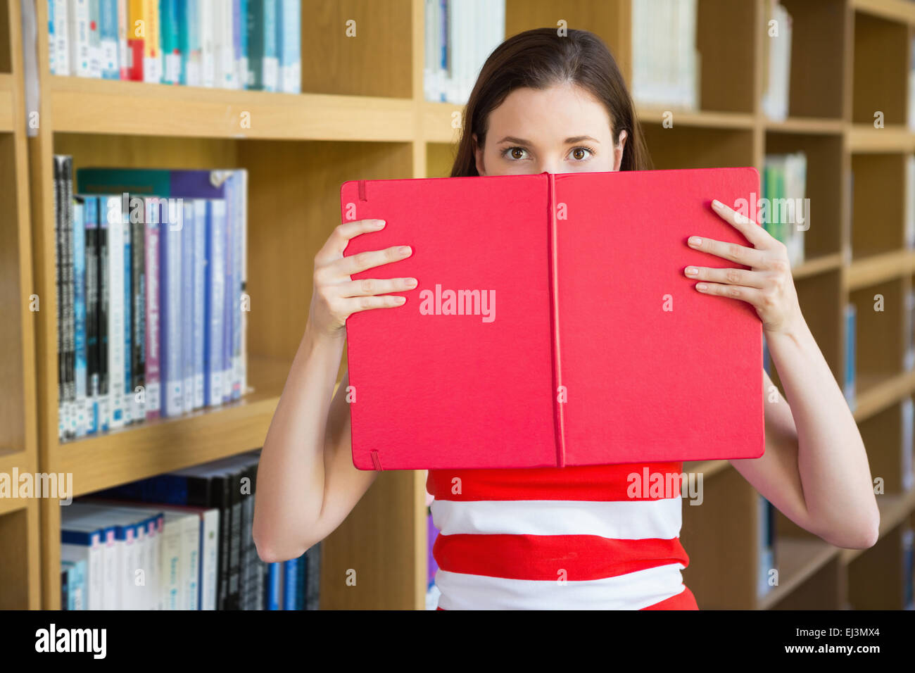 Student holding book over face Stock Photo - Alamy