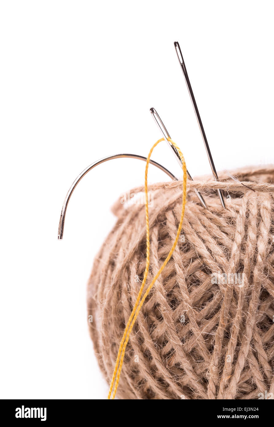 a needle stuck into the brown skein of thread on a white background Stock Photo - Alamy