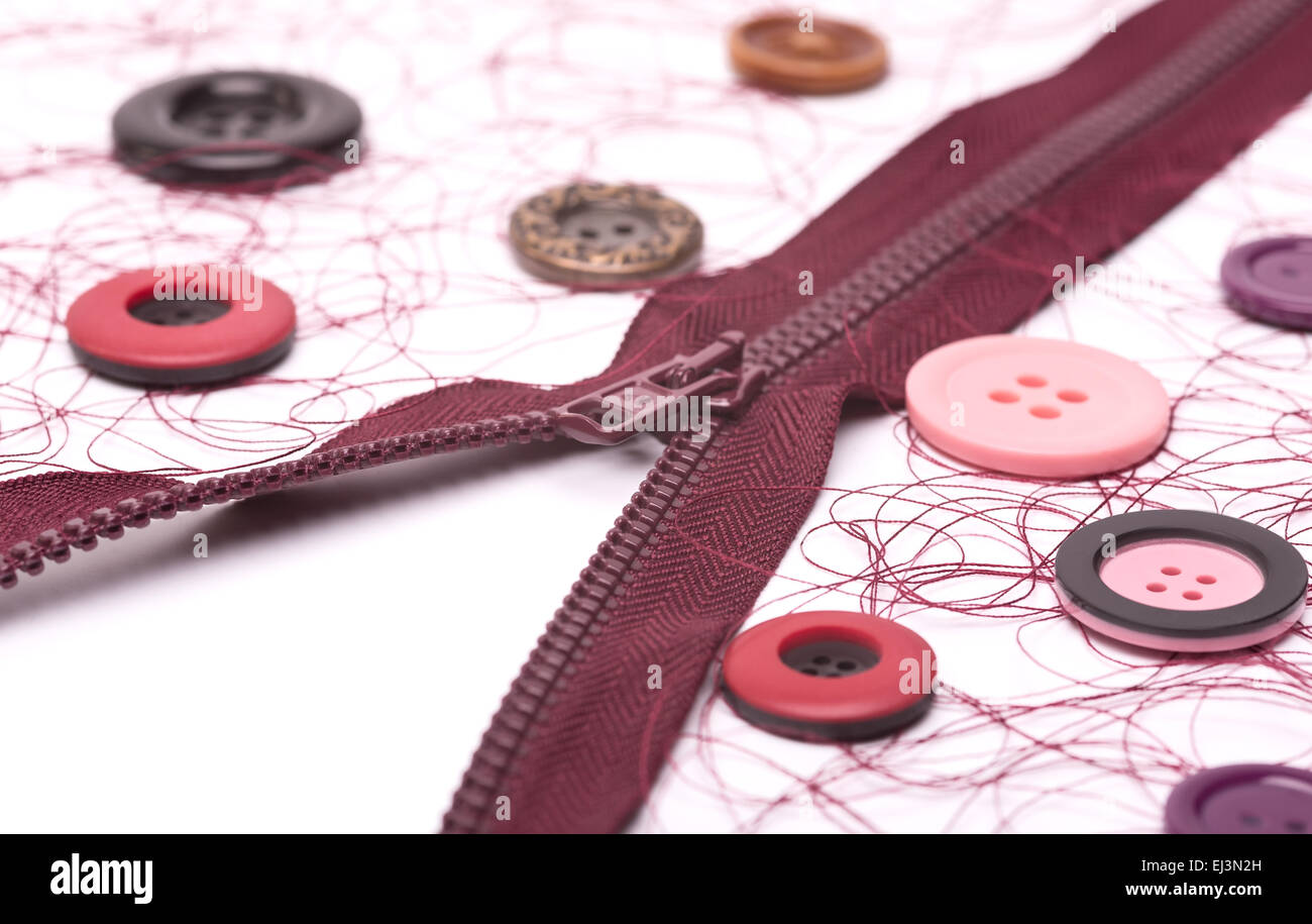 maroon zipper, scattered threads and buttons in different shapes and ...