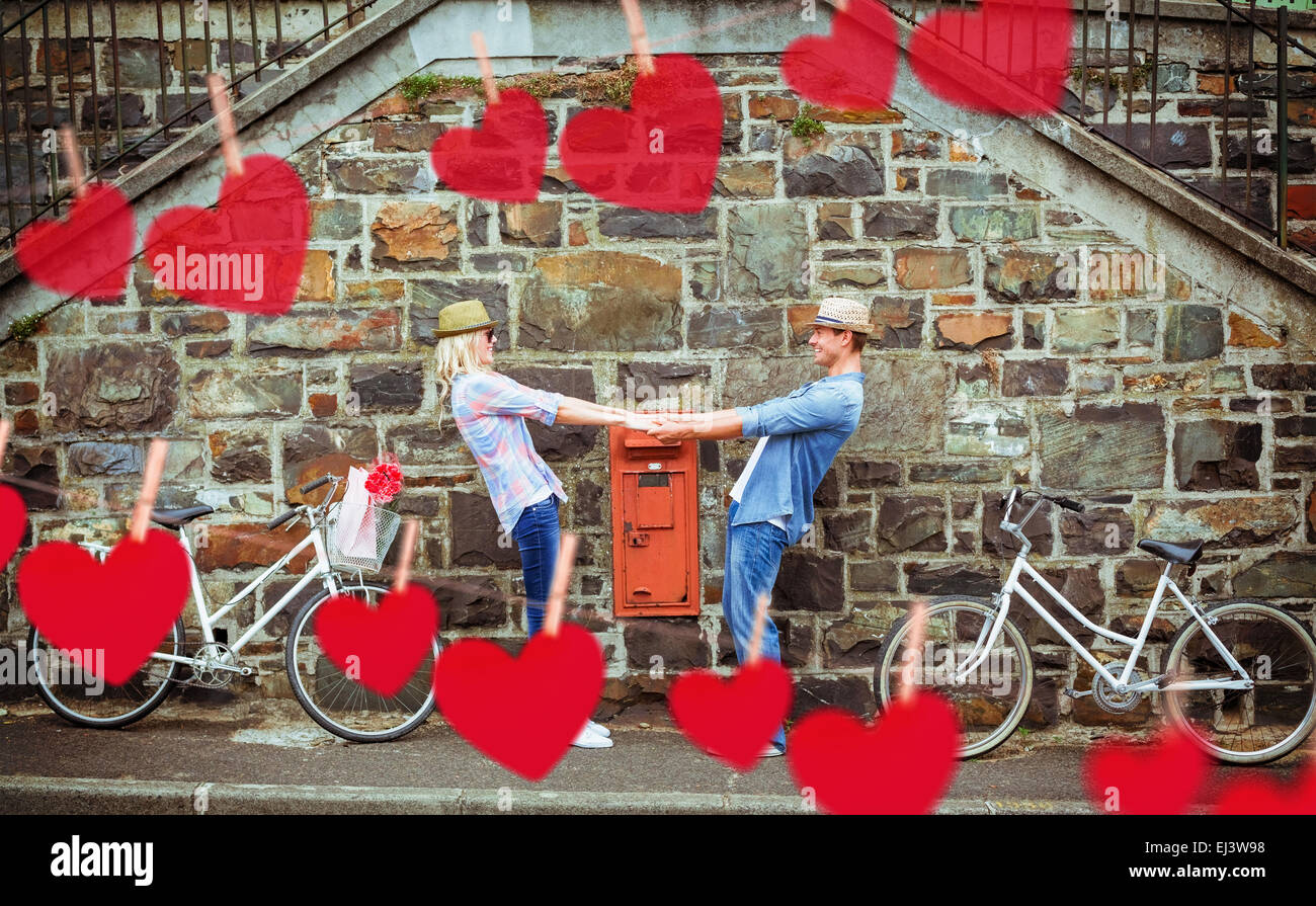 Composite image of hip young couple dancing by brick wall with their ...