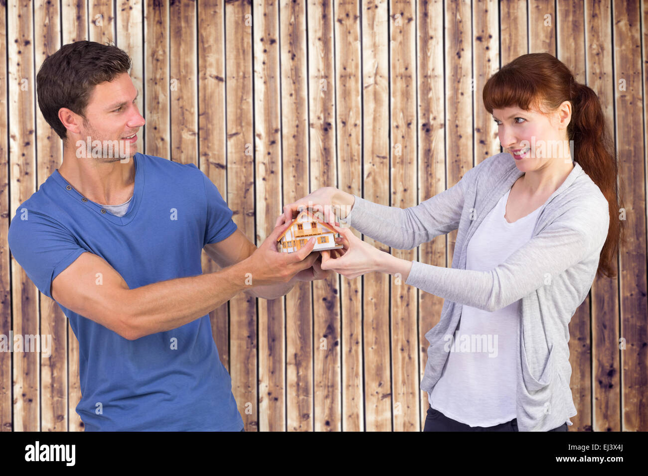Composite image of couple pulling a model house Stock Photo - Alamy