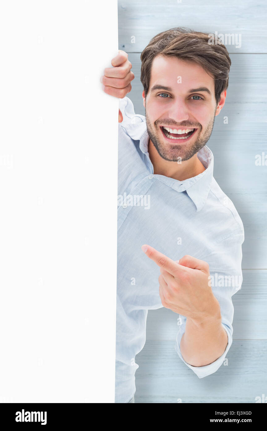 Composite image of attractive young man smiling and holding poster ...