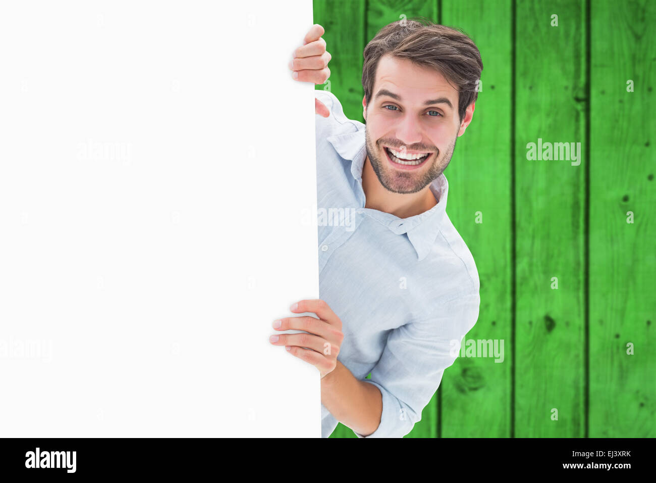 Composite image of attractive young man smiling and holding poster ...