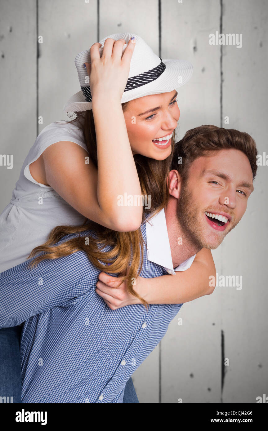 Composite image of smiling young man carrying woman Stock Photo - Alamy
