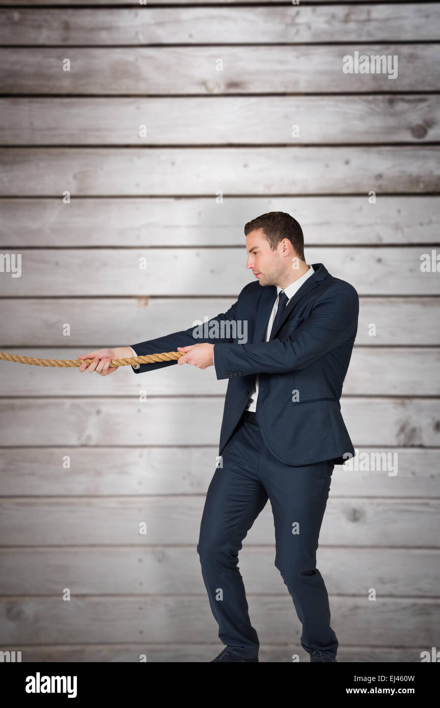 Composite image of young businessman pulling a rope Stock Photo - Alamy