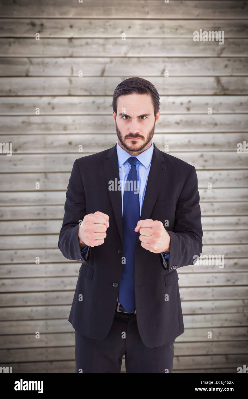 Composite image of angry businessman with closed fists looking at ...
