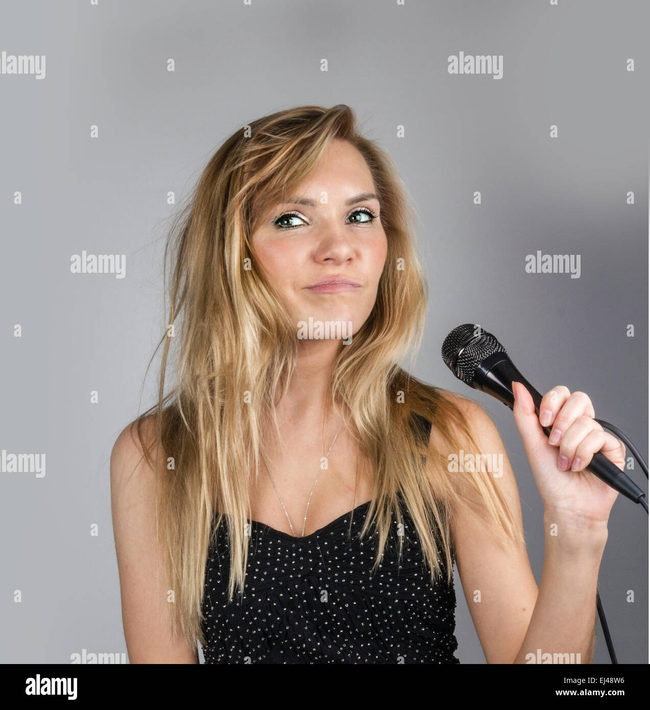 Beautiful woman singing in microphone on grey Stock Photo - Alamy
