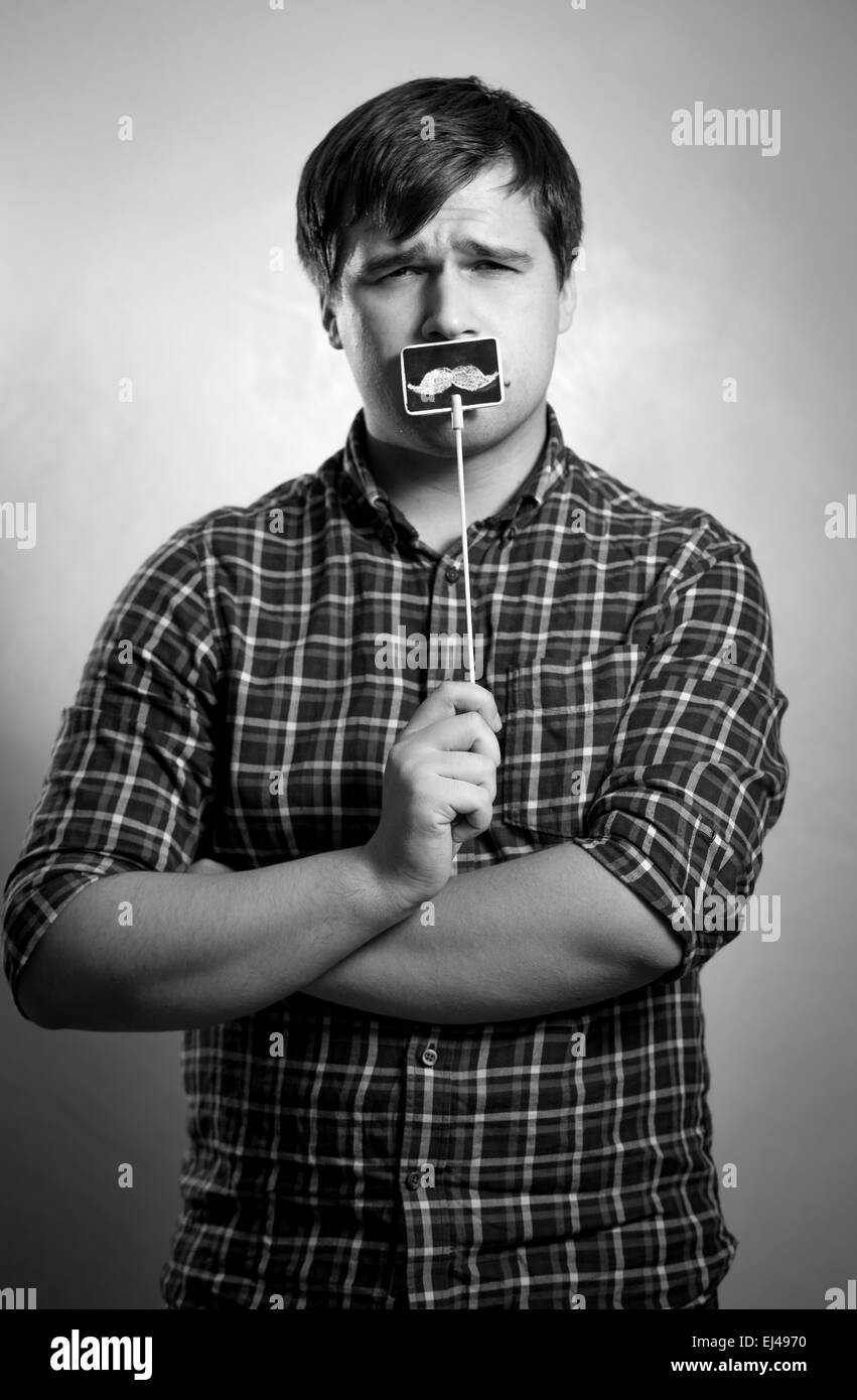 Black and white portrait of young hipster guy posing with fake mustache ...