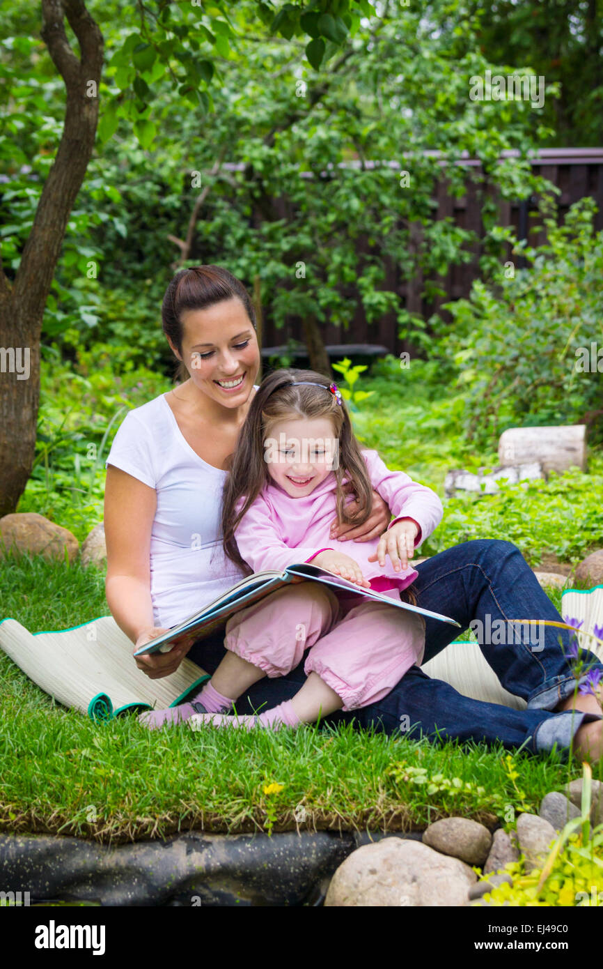Mother and daughter read book outdoors education Stock Photo - Alamy