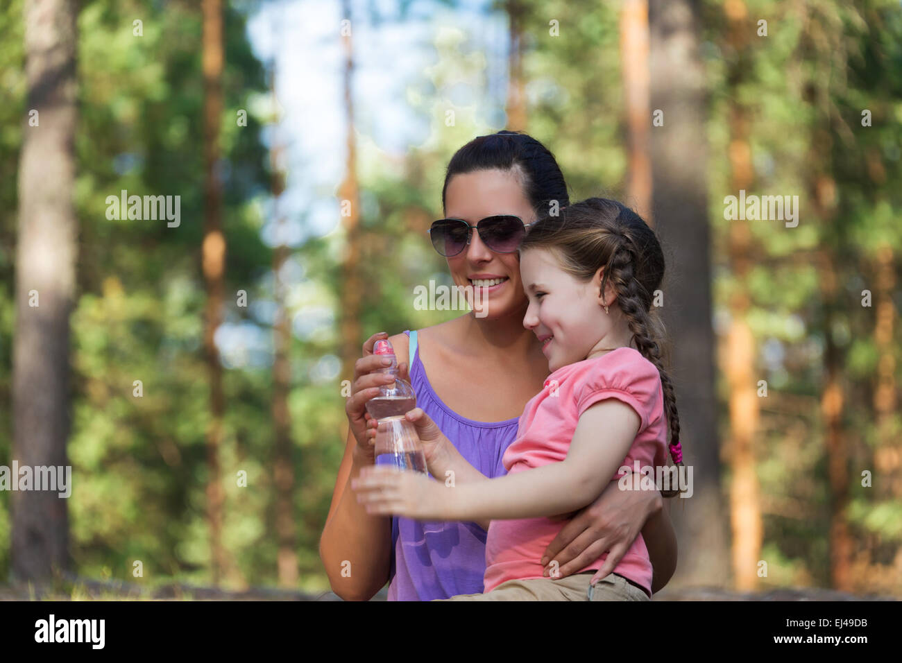 Little girl drinks water outdoors with her mum Stock Photo - Alamy