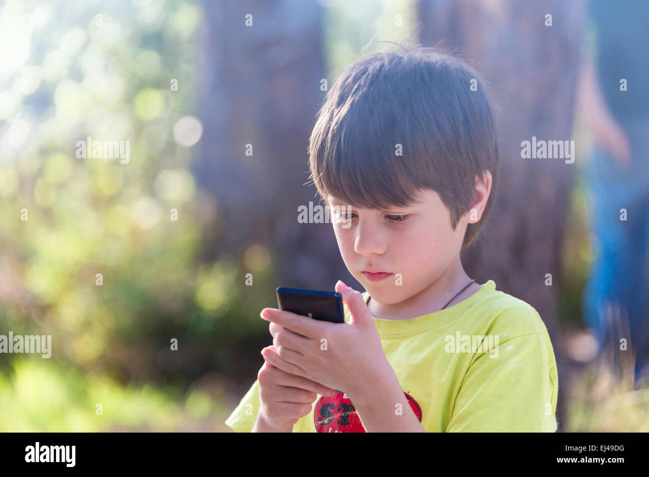 Child little boy playing mobile phone outdoors Stock Photo - Alamy