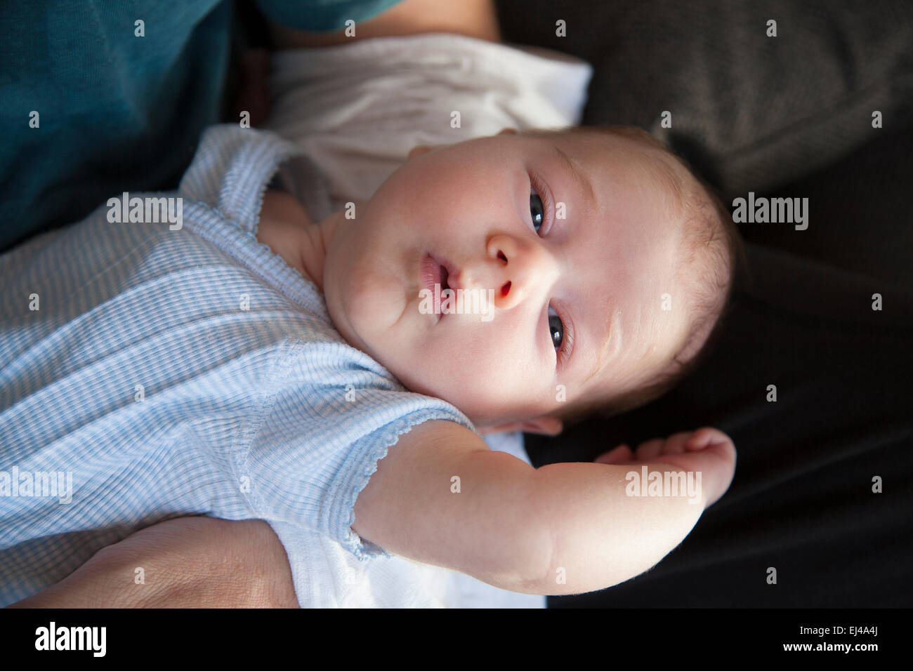 one month age newborn baby face open eyes looking at camera on man ...