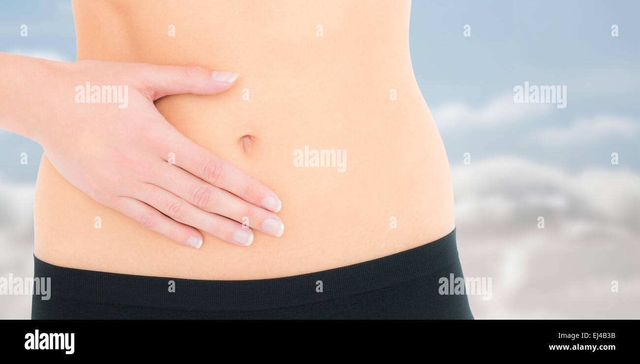 Composite image of closeup mid section of a fit woman with stomach pain ...