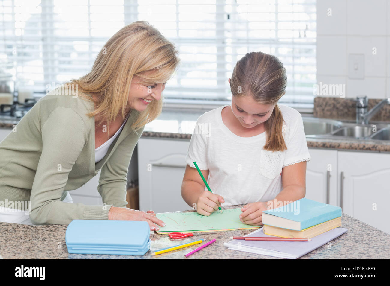 Happy mother helping daughter doing homework Stock Photo - Alamy