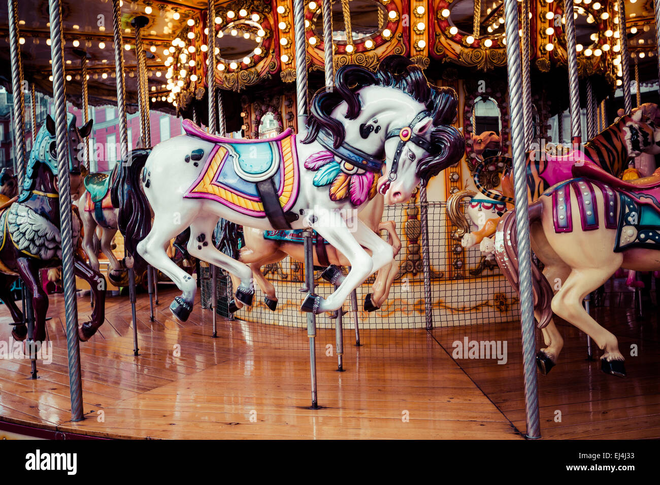 Old French carousel in a holiday park. Three horses and airplane on a ...