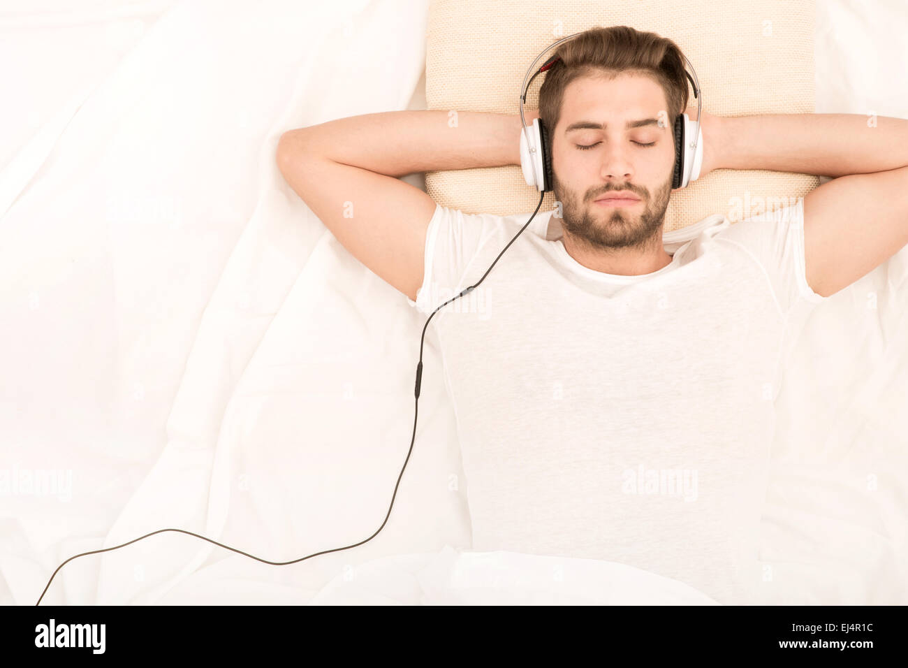 Portrait of a handsome man from above with headphones in bed Stock ...