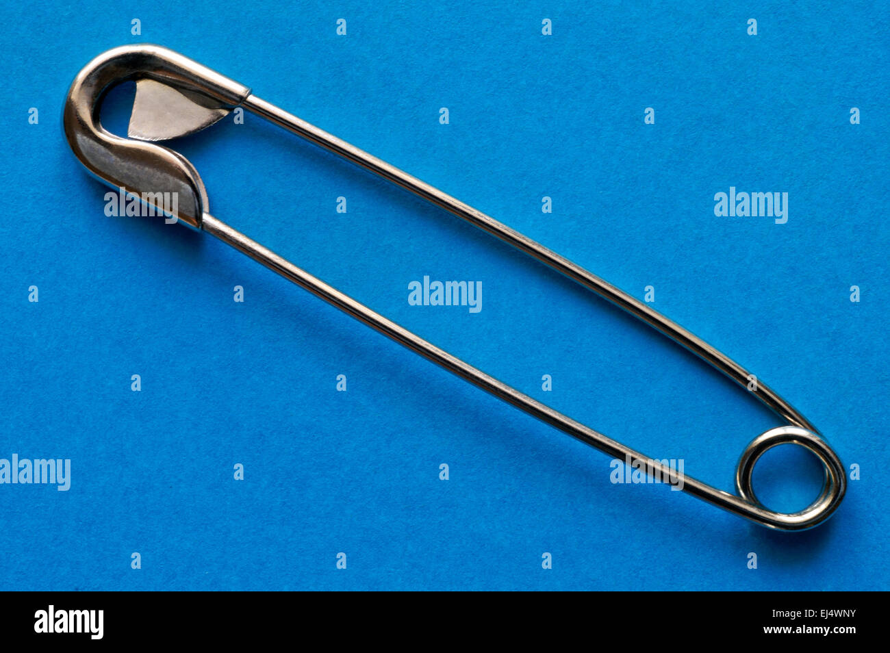 Safety pin in blue background closeup Stock Photo - Alamy