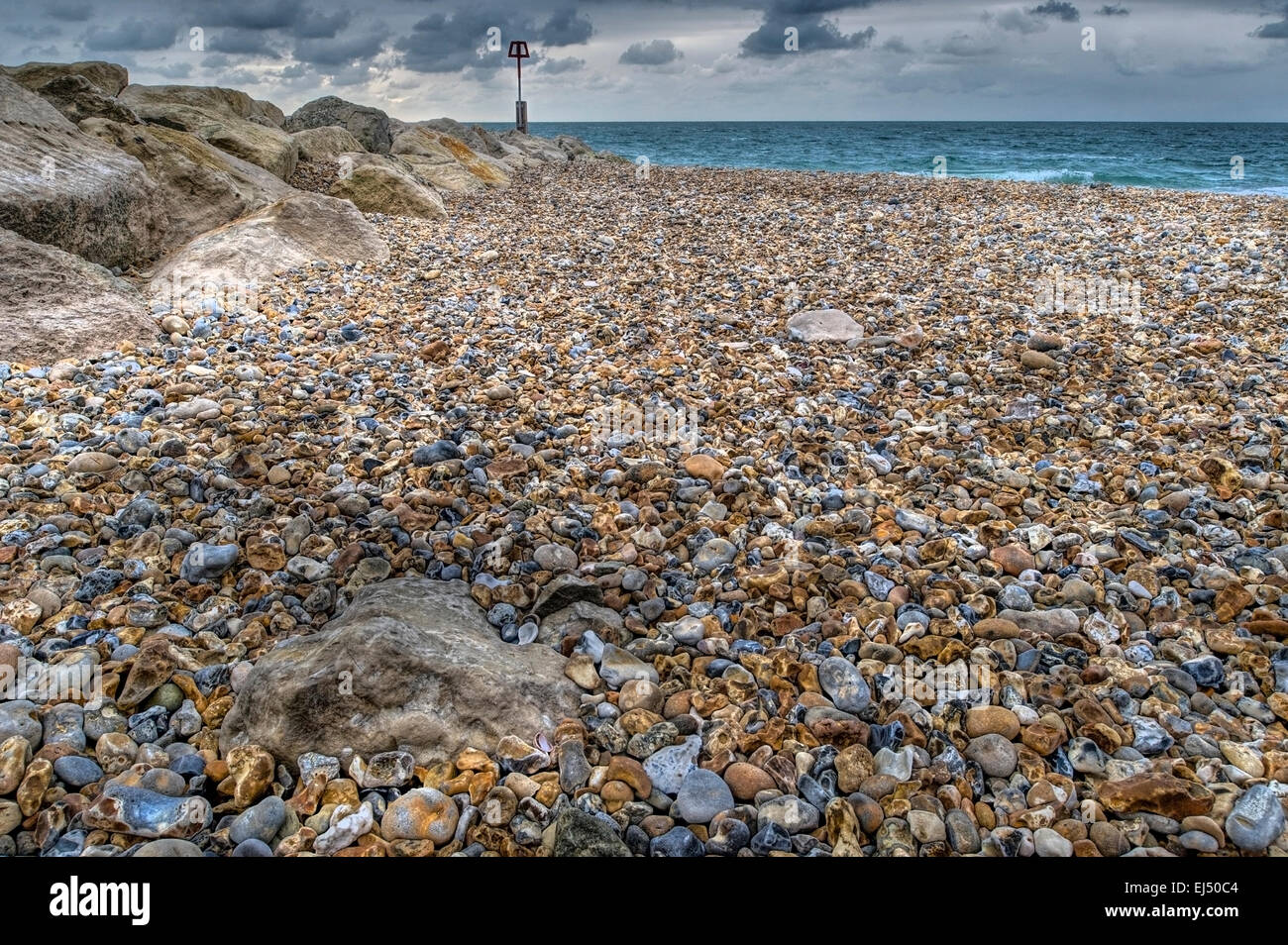 blue sea on pebble beach and breakwater Stock Photo - Alamy
