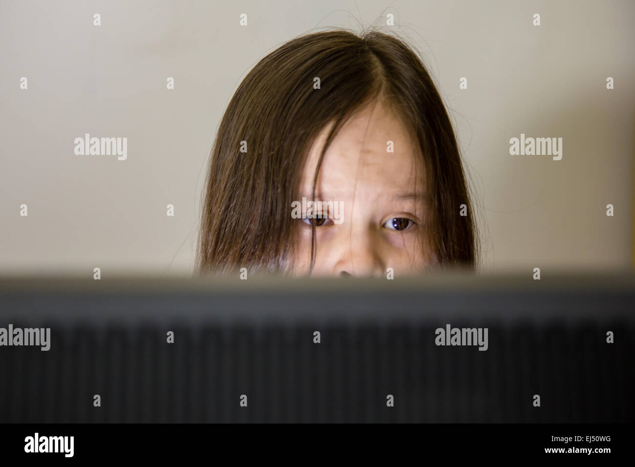 Young girl looking at computer screen, frowning Stock Photo - Alamy