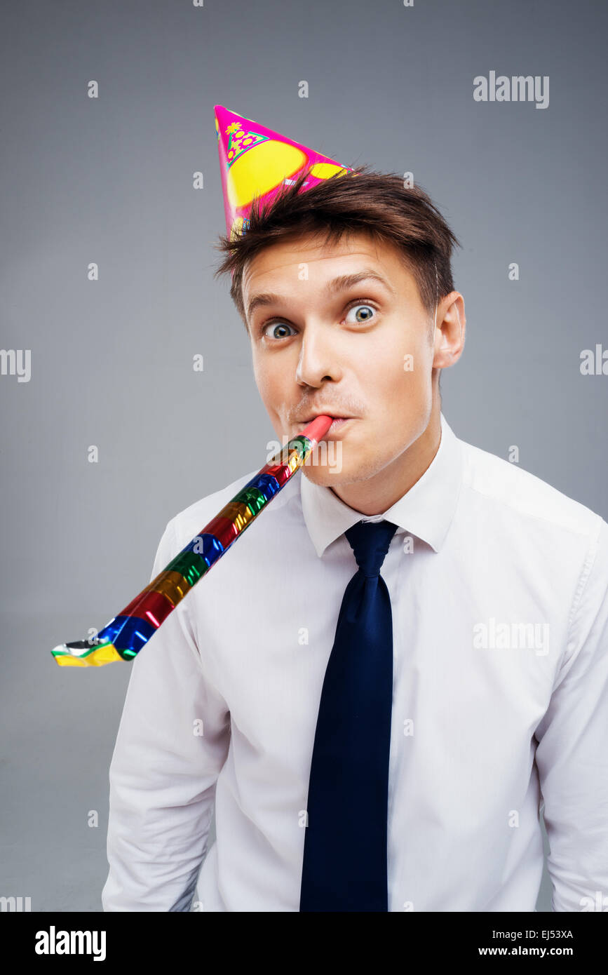 Young office manager with party hat and blower Stock Photo - Alamy