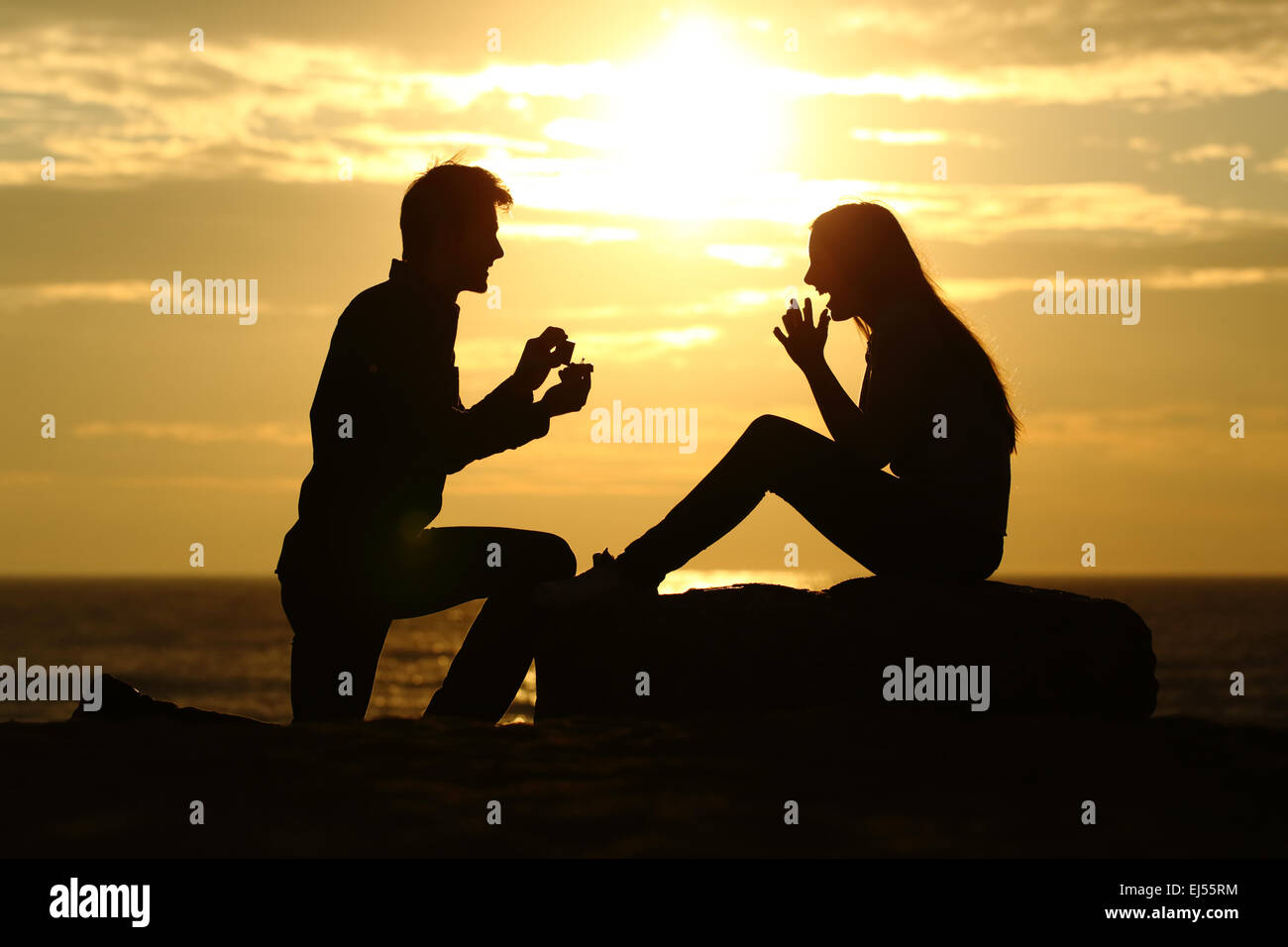 Proposal on the beach with a man silhouette asking for marry at sunset ...