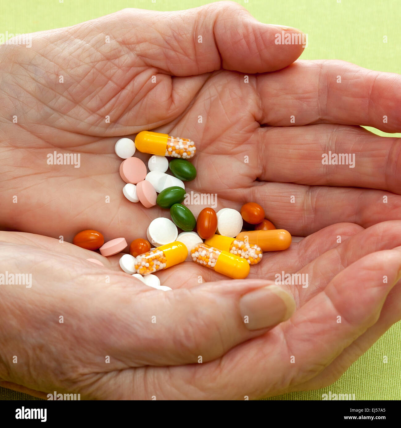 Senior woman holding assorted tablets and capsules in her cupped hands ...