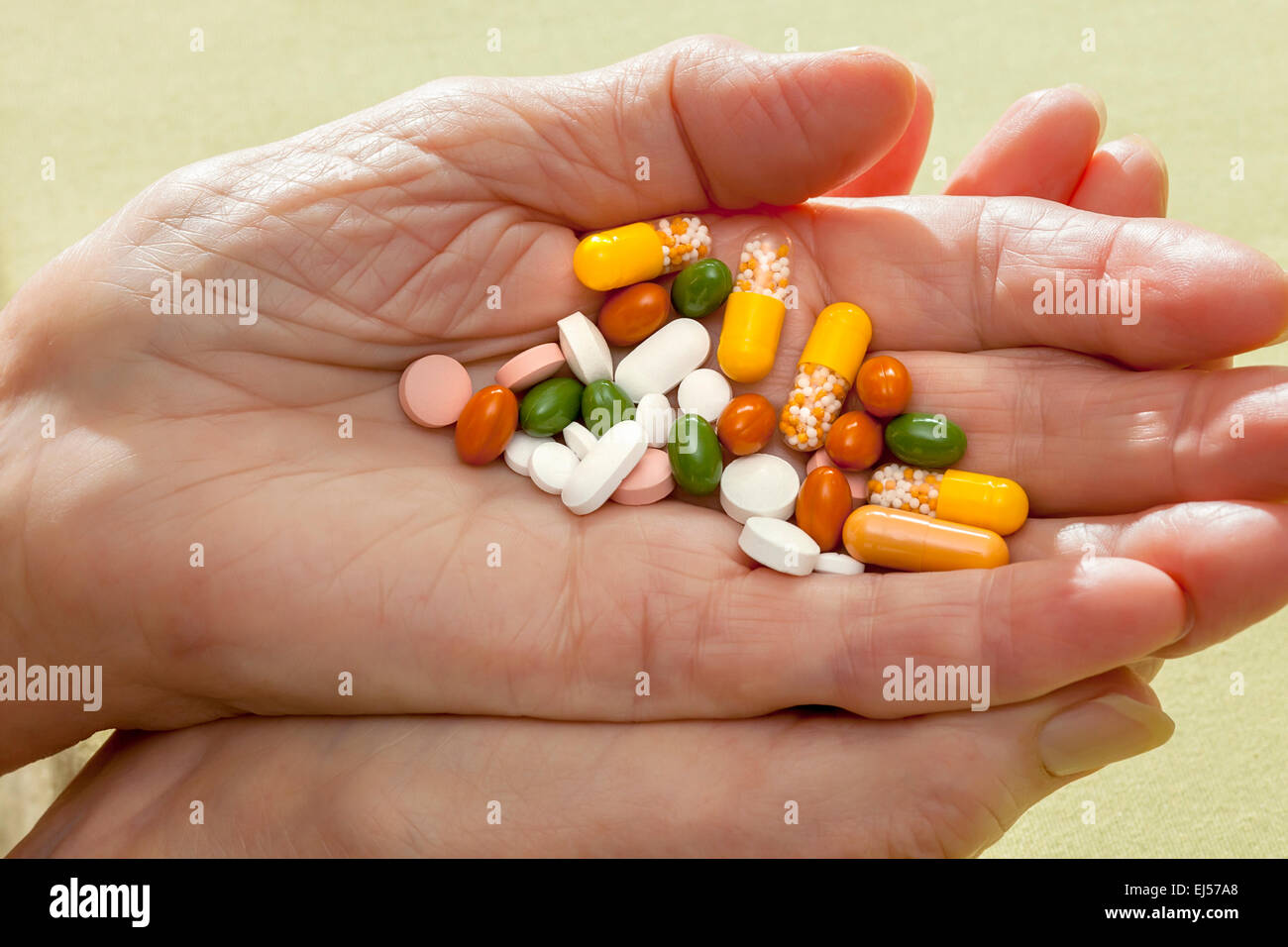 Cocktail of assorted pills capsules and tablets held in the open palm ...