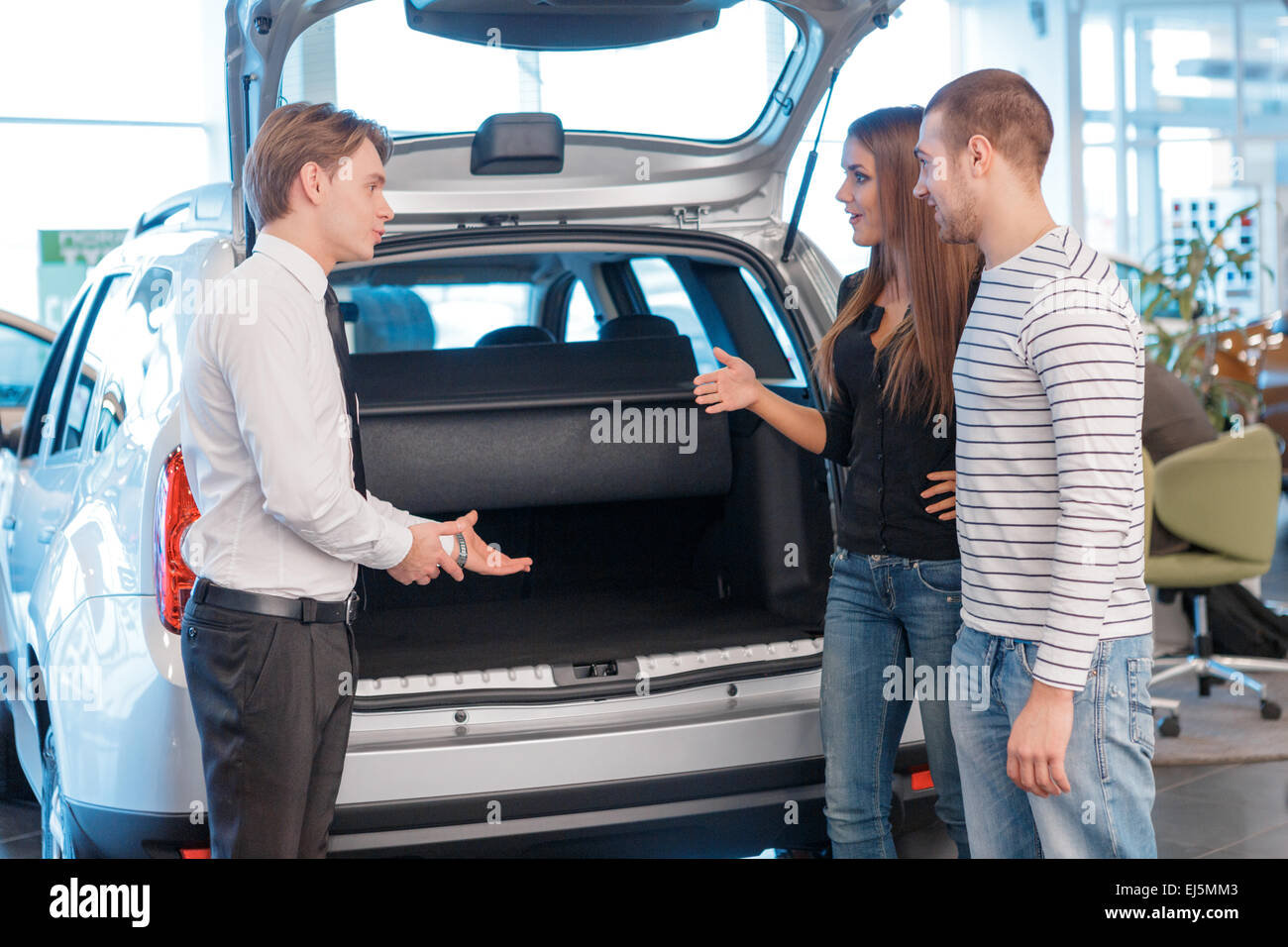 Salesman displaying trunk of the car to customers Stock Photo - Alamy