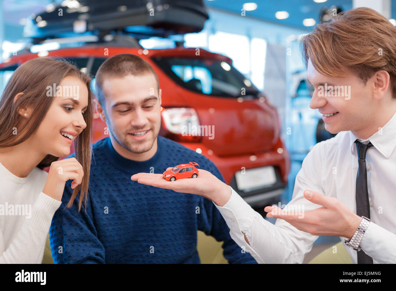 Salesman demonstrates toy car model to customers Stock Photo - Alamy