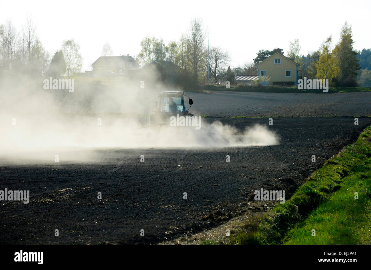 Farming, tractor pulling a harrow in dry field, lots of dust in the air ...