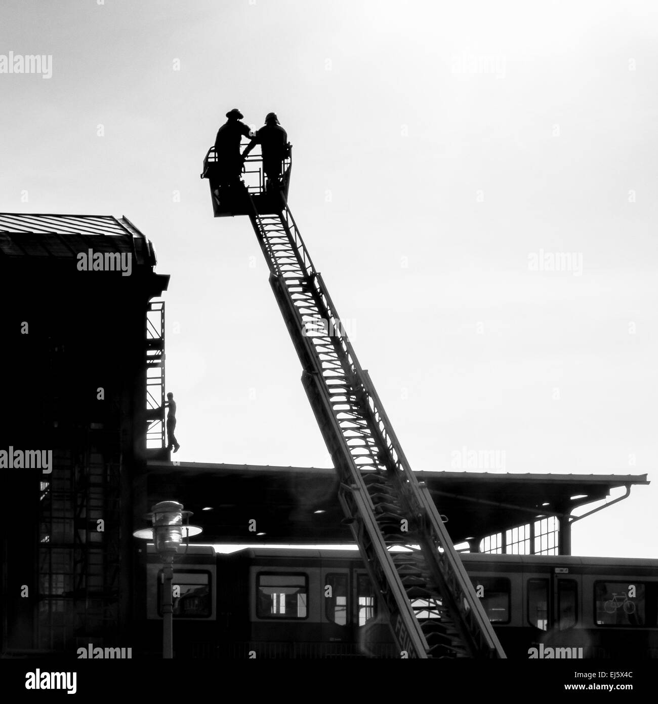 Two firemen on fire-engine ladder rescue man from top of ...