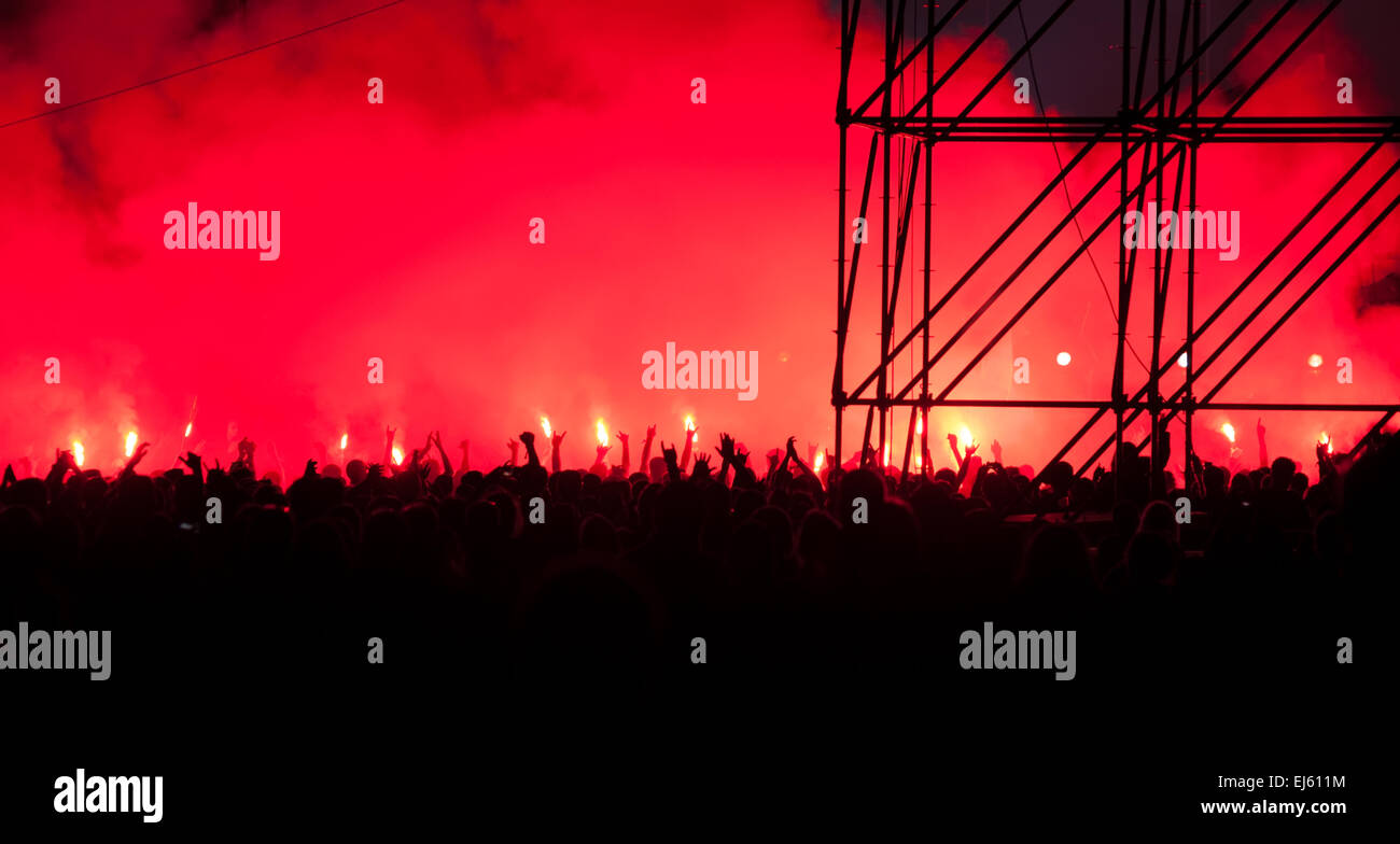 Fans burn red flares at rock concert Stock Photo - Alamy