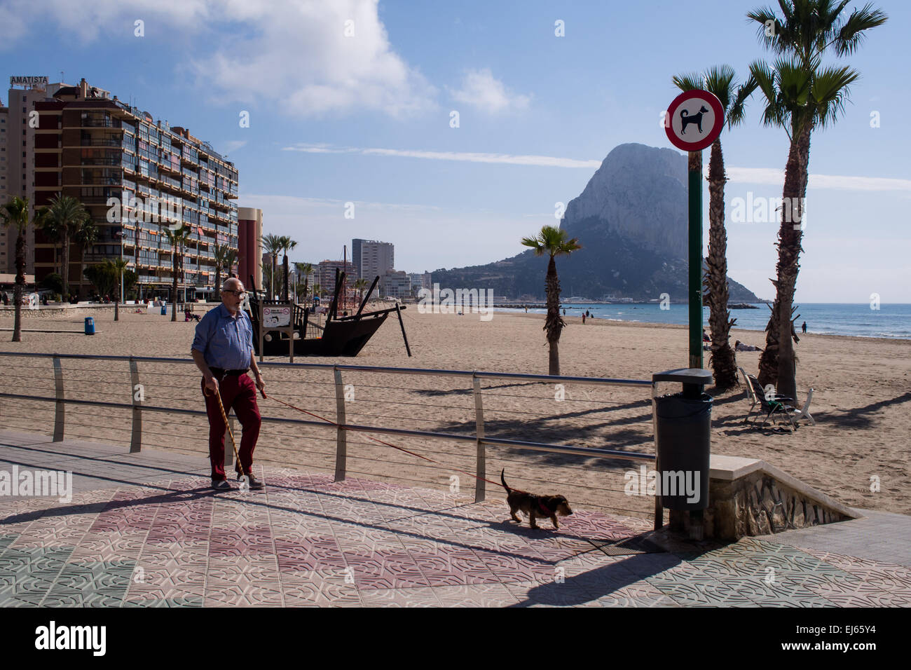 A man walks his dog along the seafront in the Spanish resort of Calpe ...