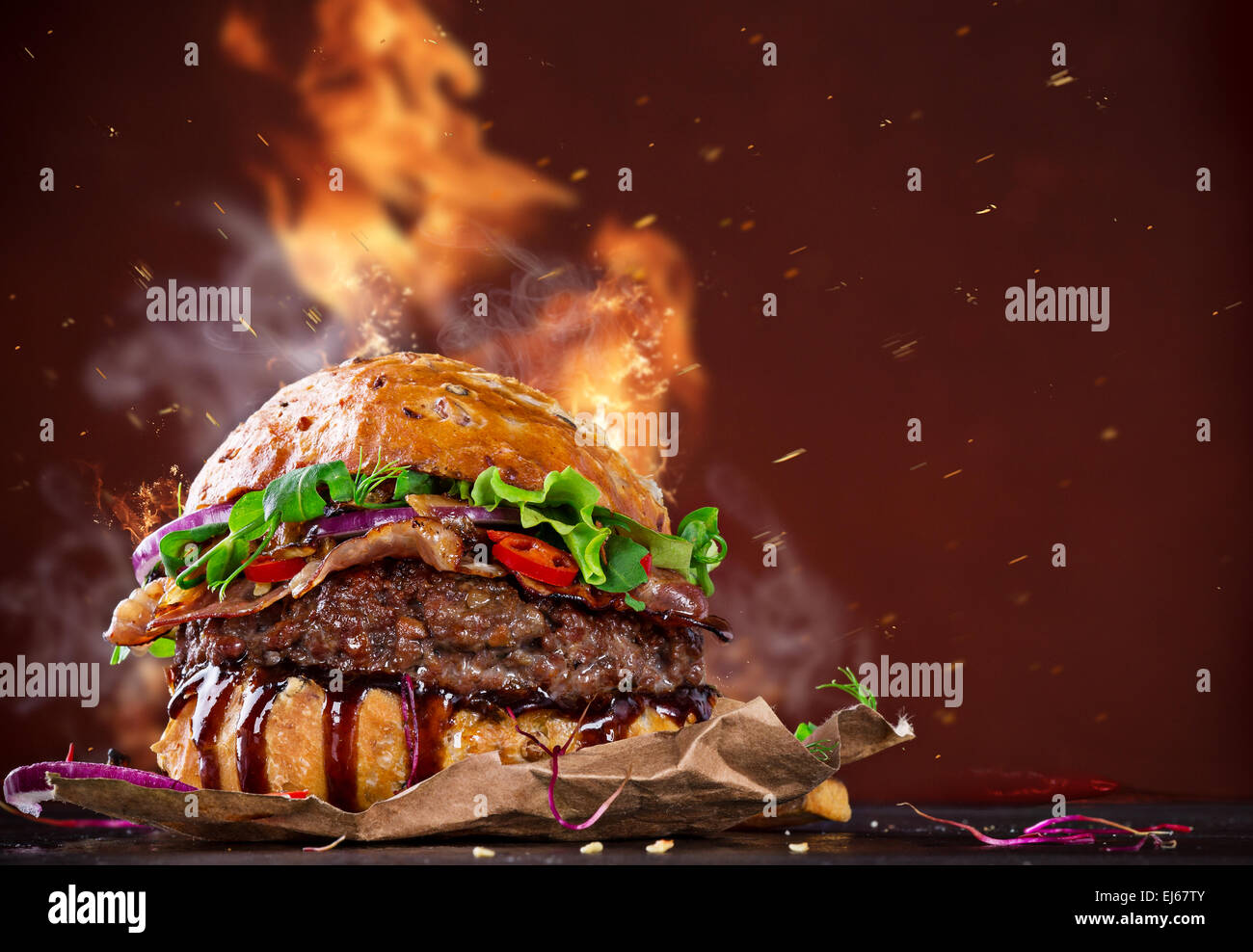 Delicious hamburger with fire flames on wooden background Stock Photo ...
