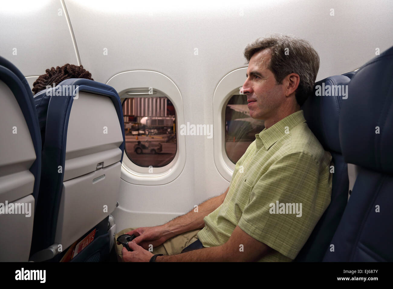 Man sits on airplane in airplane seat next to airplane window Stock ...