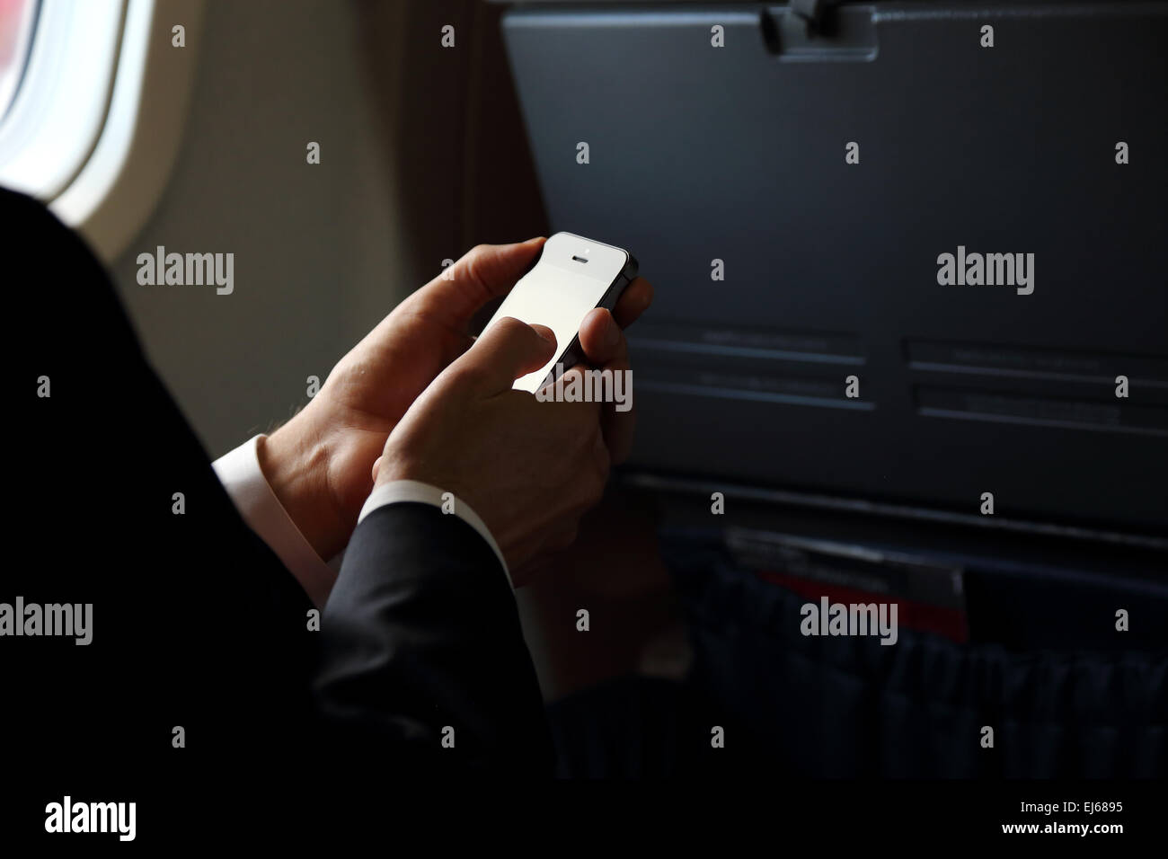 Man uses phone on airplane in airplane seat, hands Stock Photo - Alamy