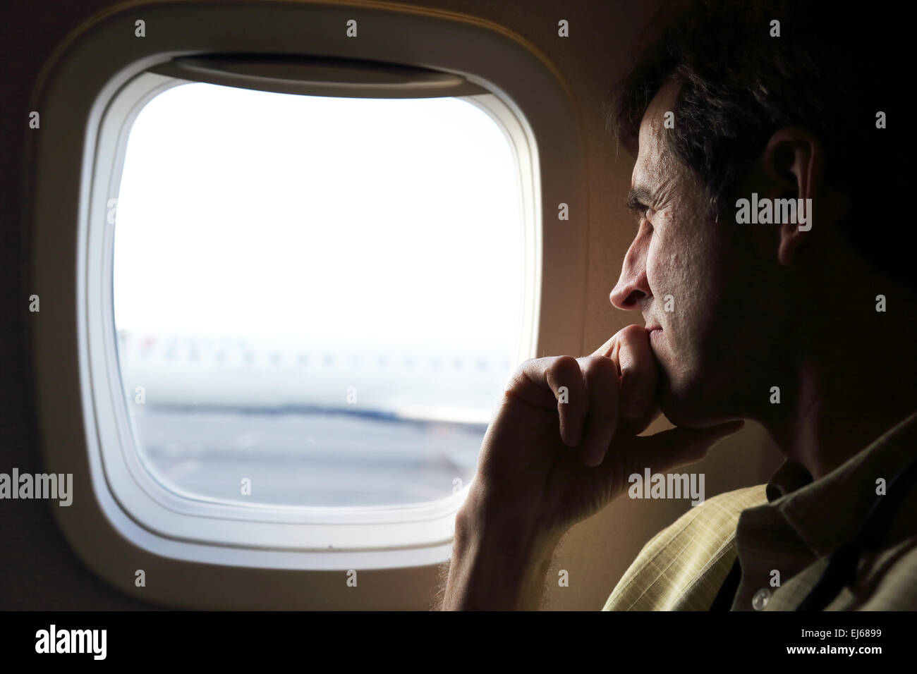 Passenger on airplane in airplane seat by window, man looking anxious ...