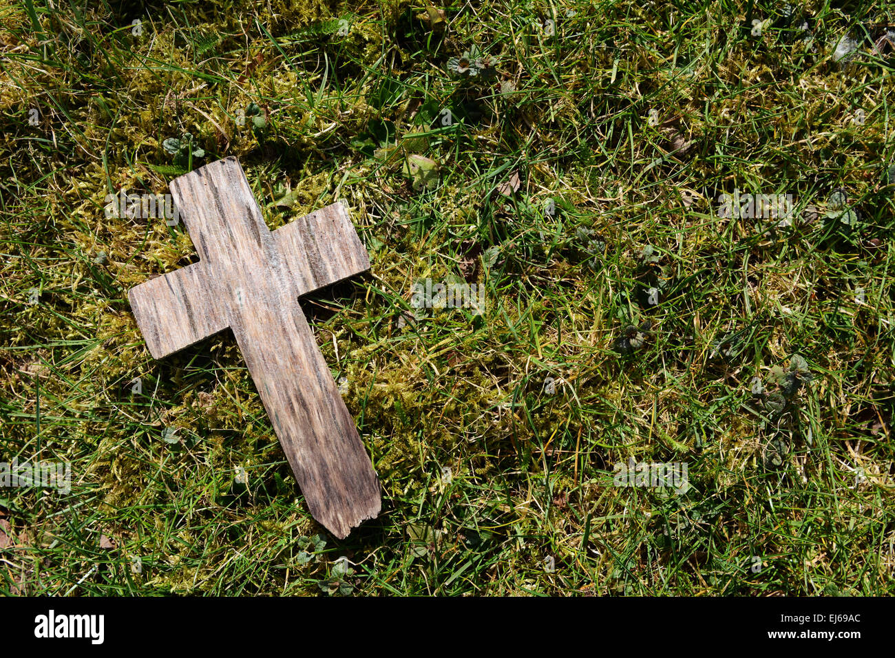 Small weathered cross on a background of grass and moss with copy space ...